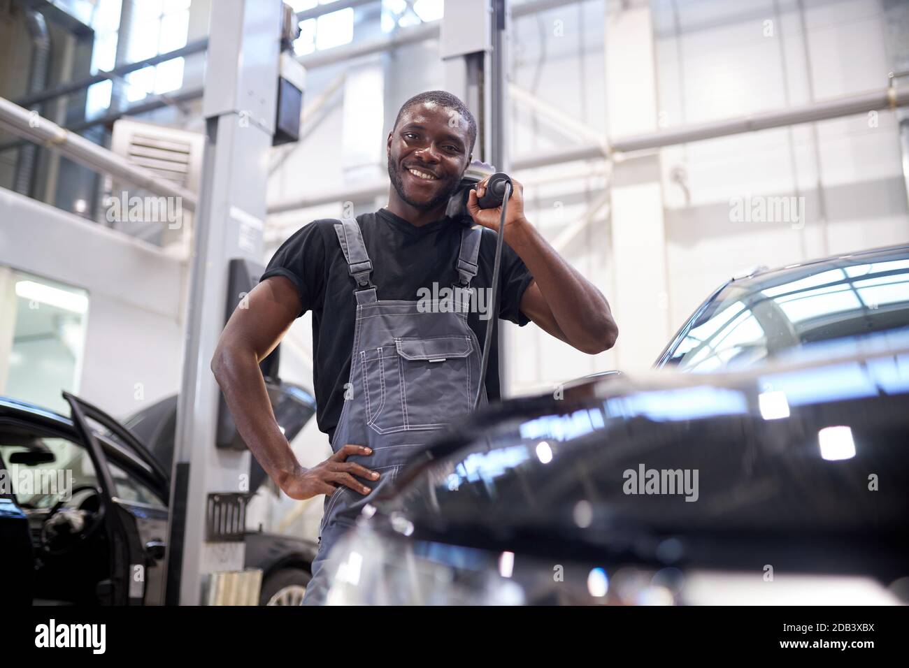 portrait of positive african man with power buffer machine for ...