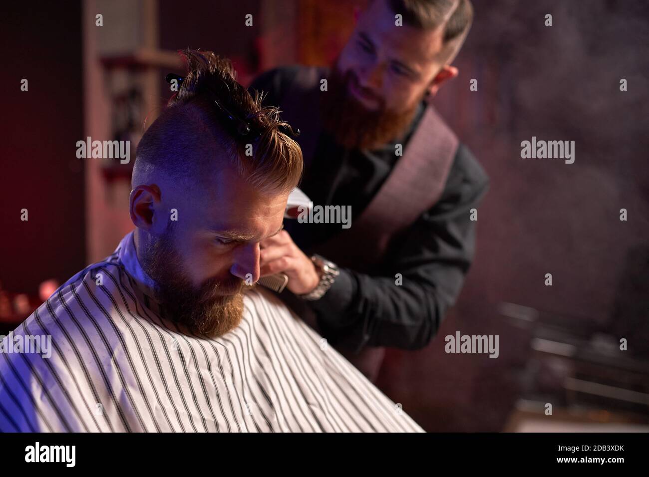 confident male hairstylist cut hair to elegant stylish man sitting in ...