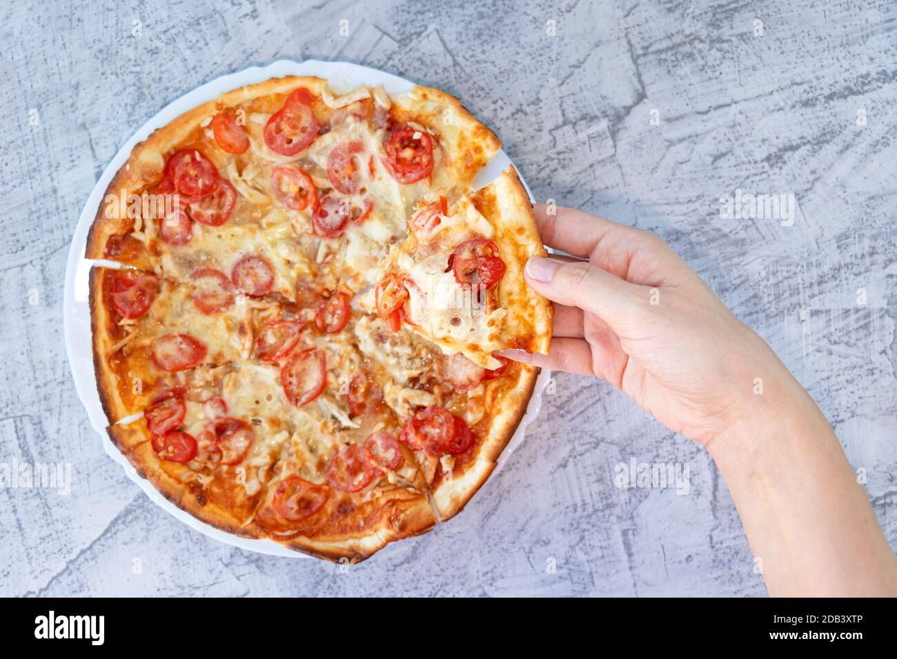 Female hand eating pizza on white stone background. Pizza at home ...