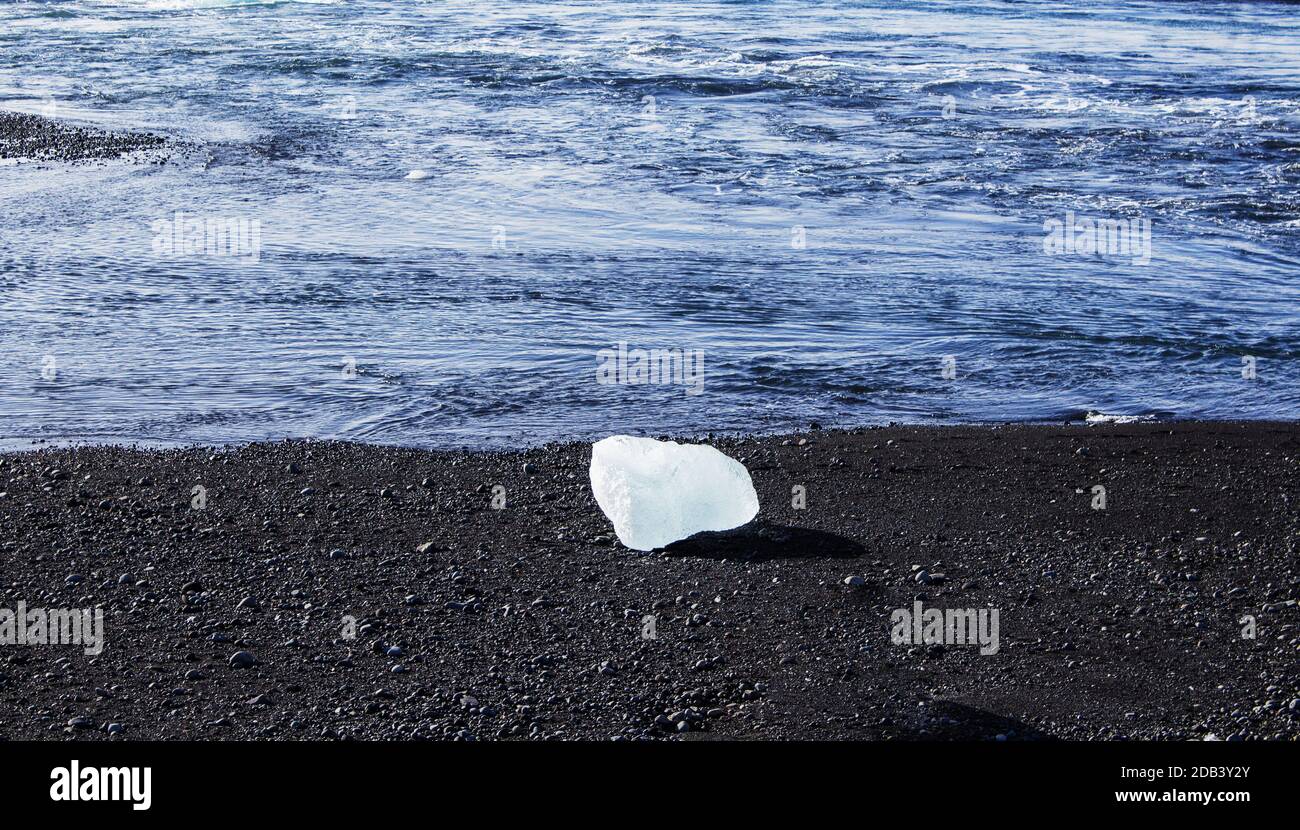 black pebble beach with a single block of ice in front of the sea Stock ...