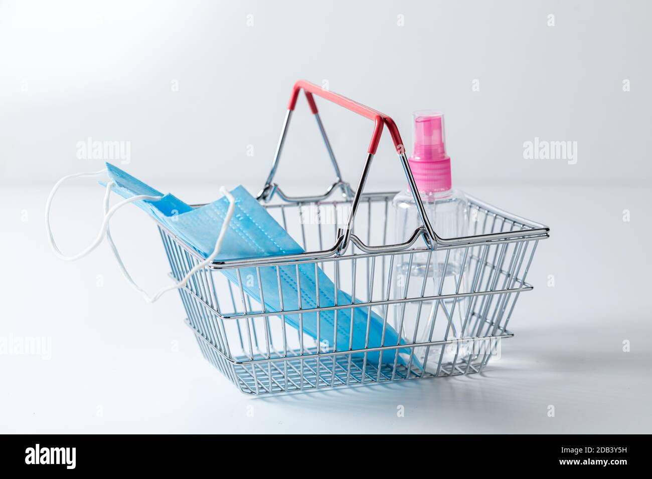 Medical mask and shopping basket as protection in supermarket on white ...