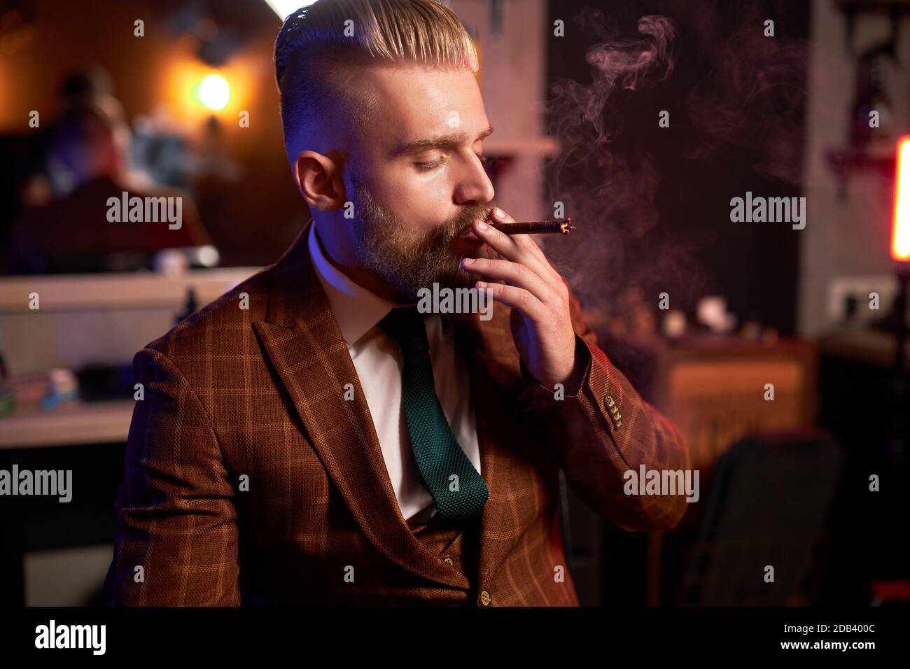 portrait of handsome adult man in a formal costume smoking a cigar ...