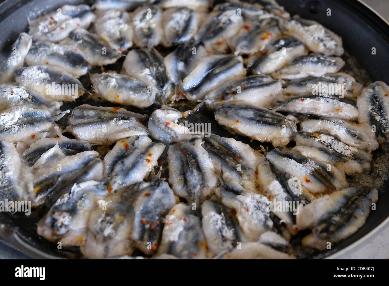 anchovy fish cooked on a stove, cooking anchovy in a pan, anchovy in a ...