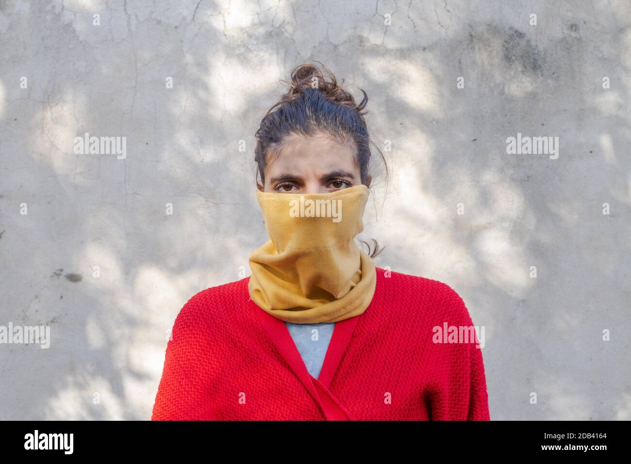 young woman with her face covered by a yellow garment with gray ...