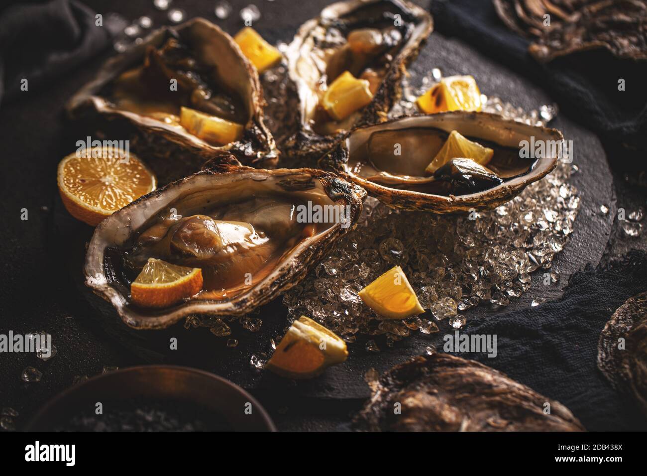Fresh oysters seafood on a black slate. Open oyster shell with lemon ...