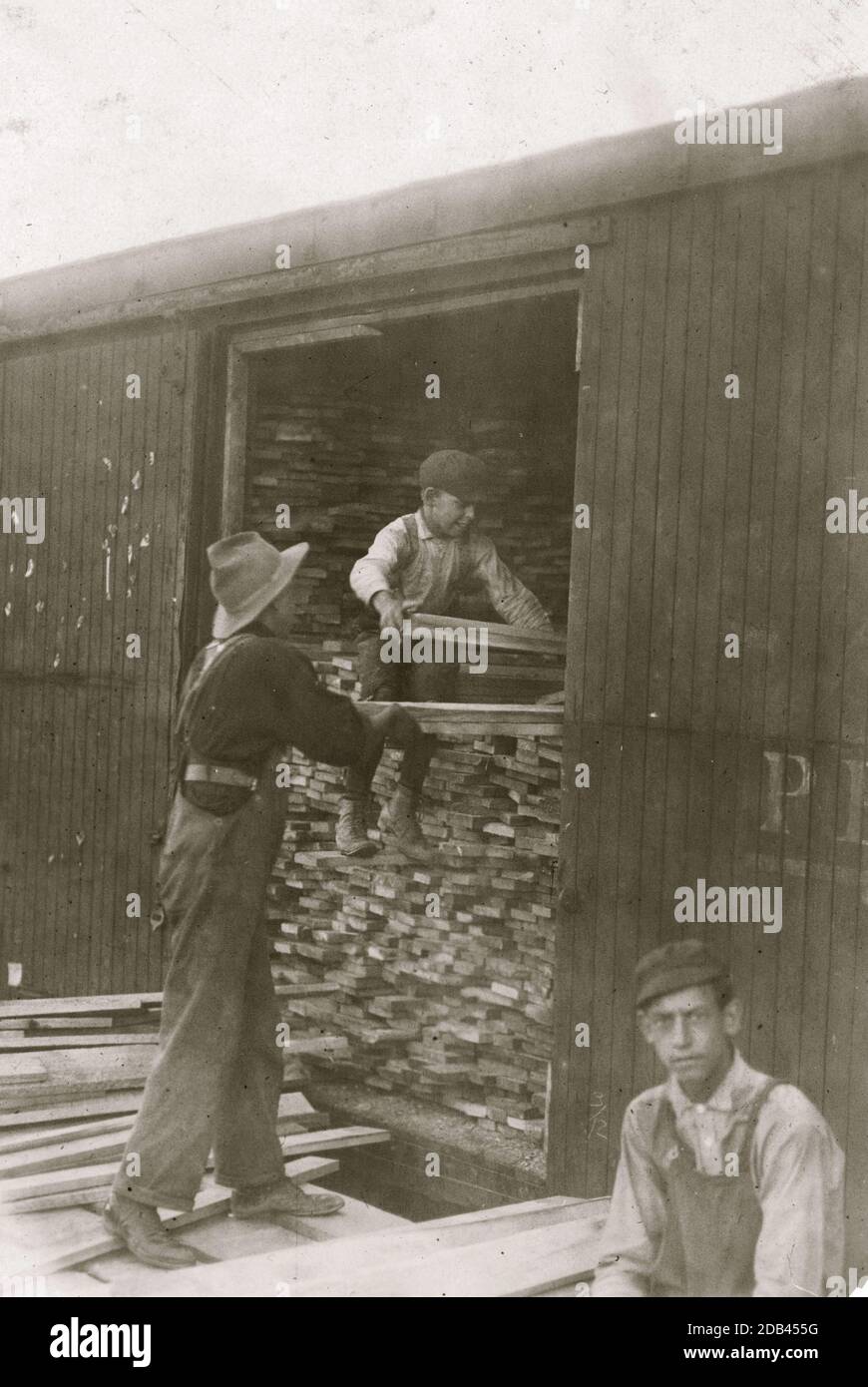 Young boy working for Hickok Lumber Co. Unloading wood from a boxcar ...