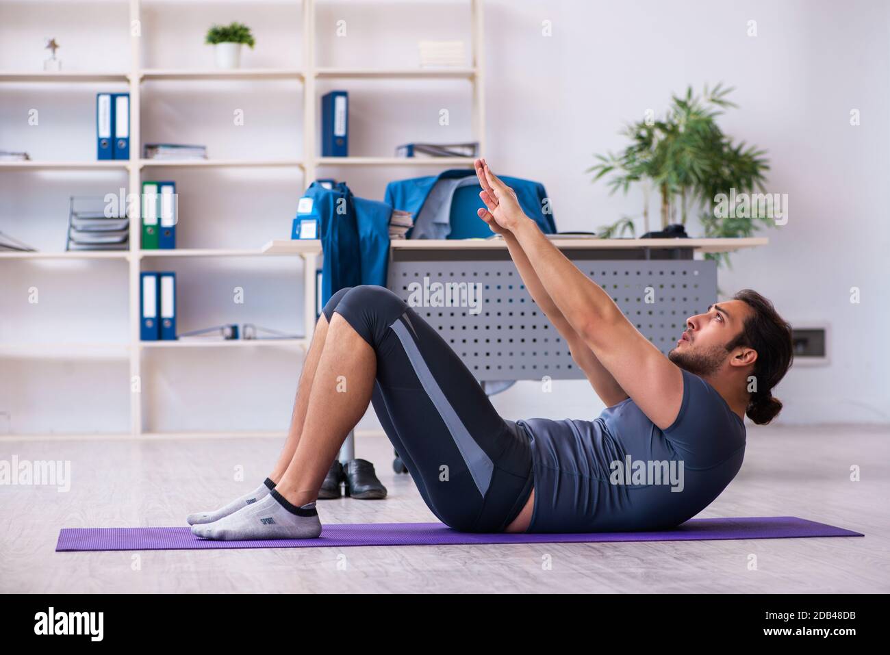 Young male employee doing sport exercises in the office Stock Photo - Alamy