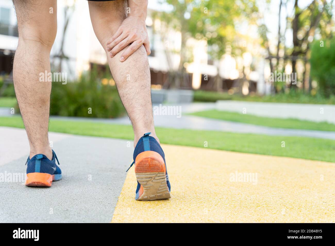 Male runner athlete leg injury and pain. Hands grab painful leg while ...