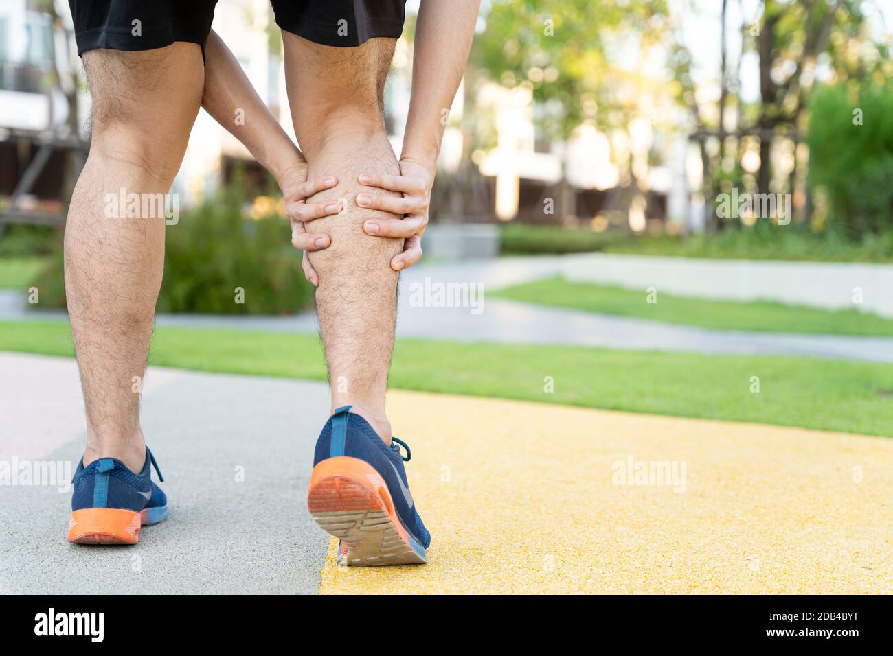 Male runner athlete leg injury and pain. Hands grab painful leg while ...