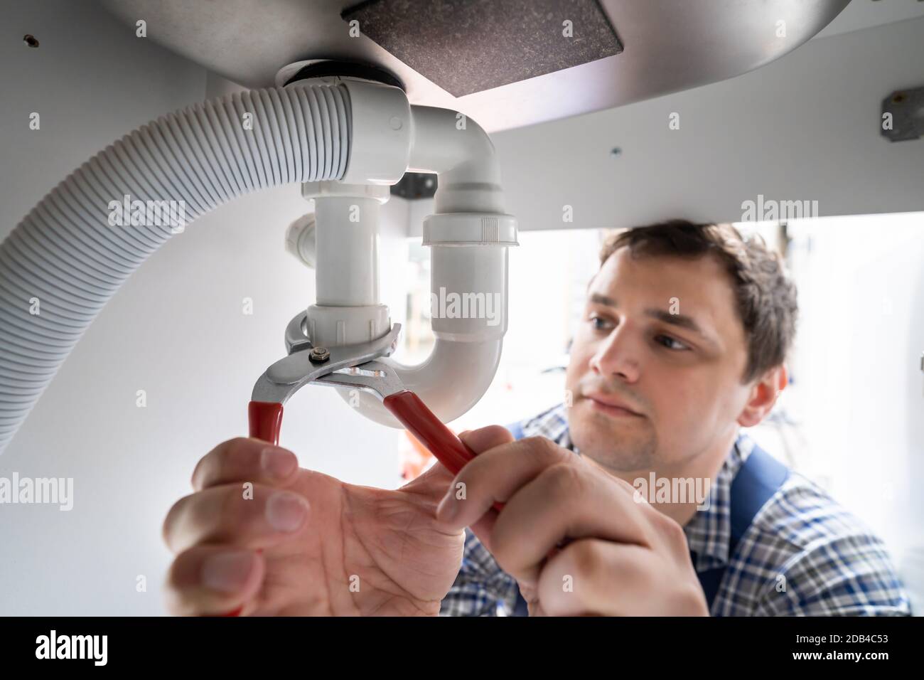 Young Plumber Working With Pipe Wrench In Kitchen Stock Photo - Alamy