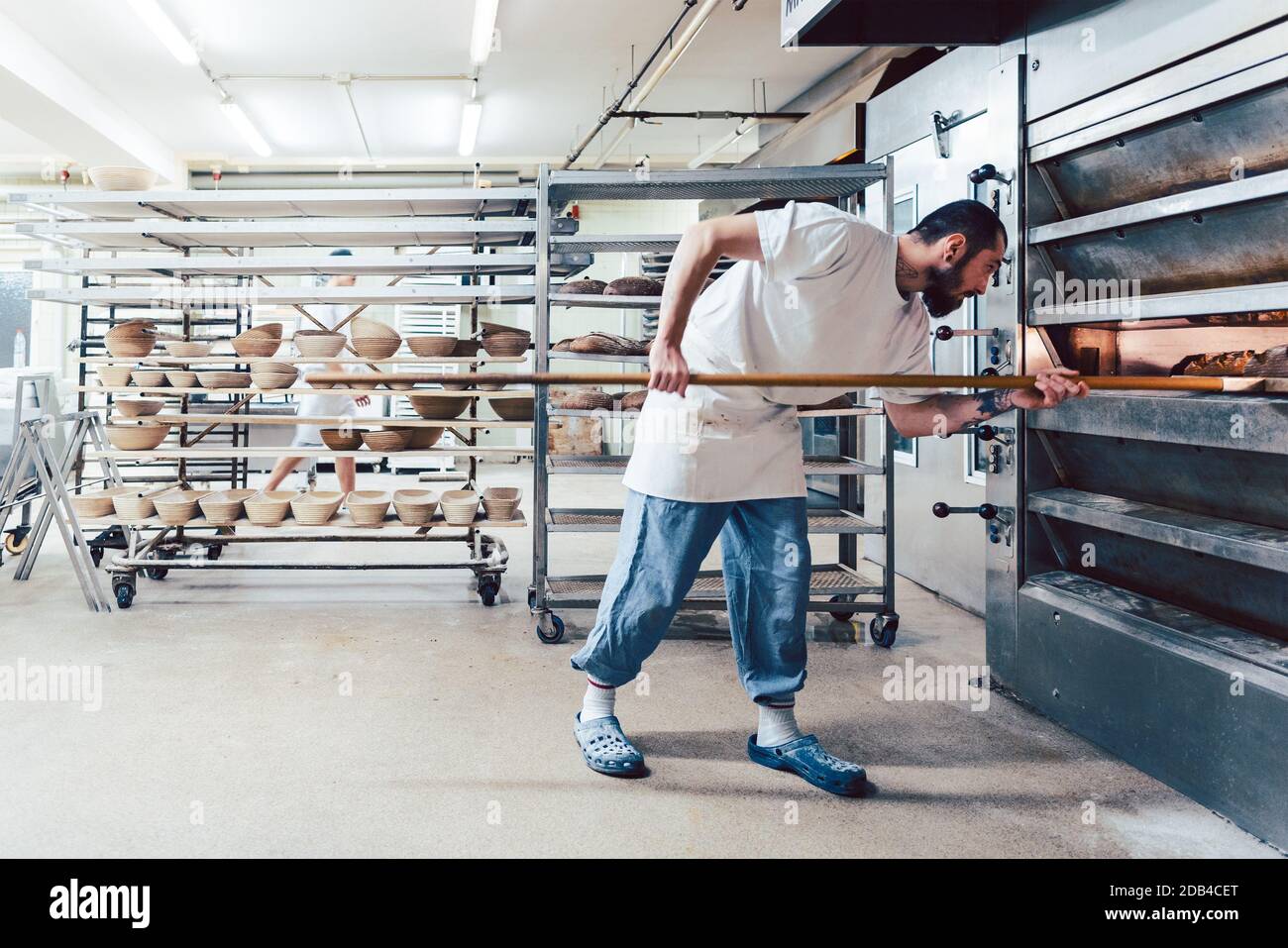 Baker checking bread in the baker oven turning his face into the camera ...
