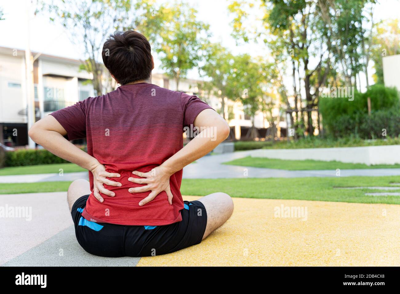 Male athlete suffering from back pain and injury. Hands grab back or ...