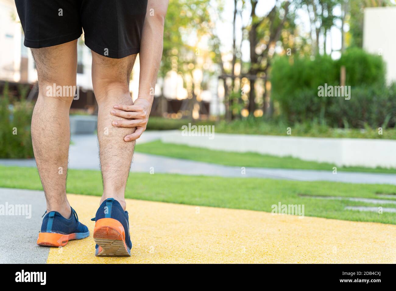 Male runner athlete leg injury and pain. Hands grab painful leg while ...