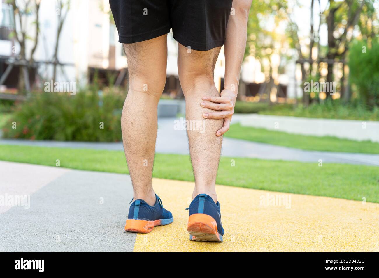 Male runner athlete leg injury and pain. Hands grab painful leg while ...
