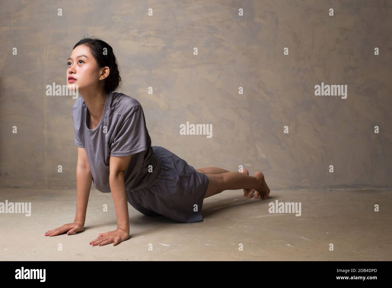 Portrait of gorgeous young asian woman practicing yoga indoor. Beautiful girl practice cobra ...