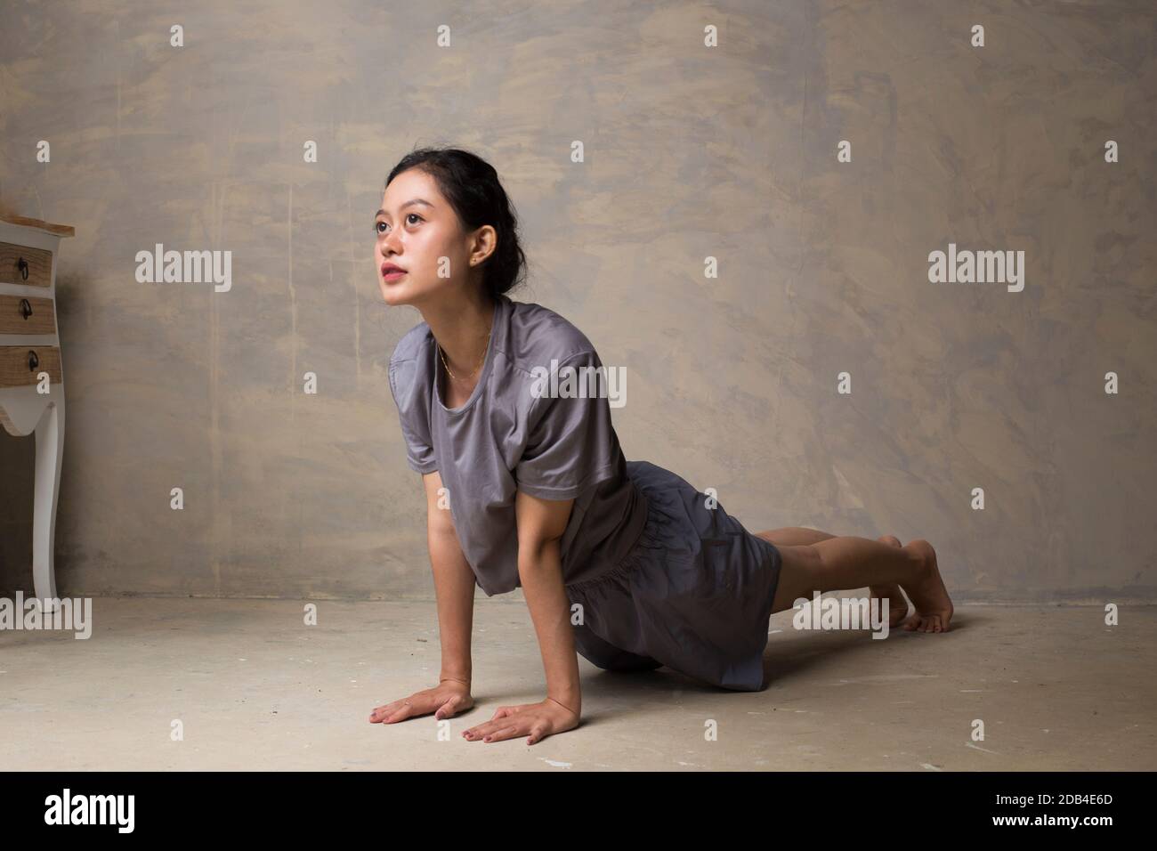 Portrait of gorgeous young asian woman practicing yoga indoor. Beautiful girl practice cobra ...