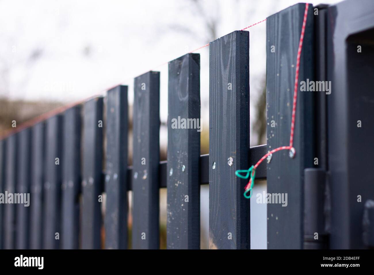 A dark gray fence made of wooden boards is set using a rope level Stock ...