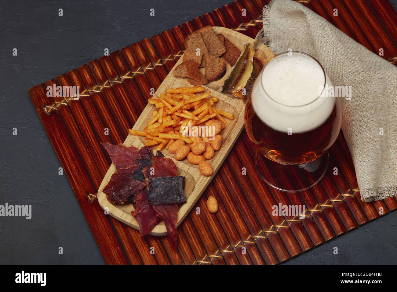 Glass with beer and set of various kind snacks: jerky, potato chips ...