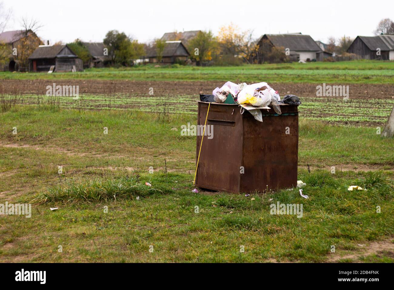 Overflowing rusty trash can in the countryside. Rubbish scattered on ...