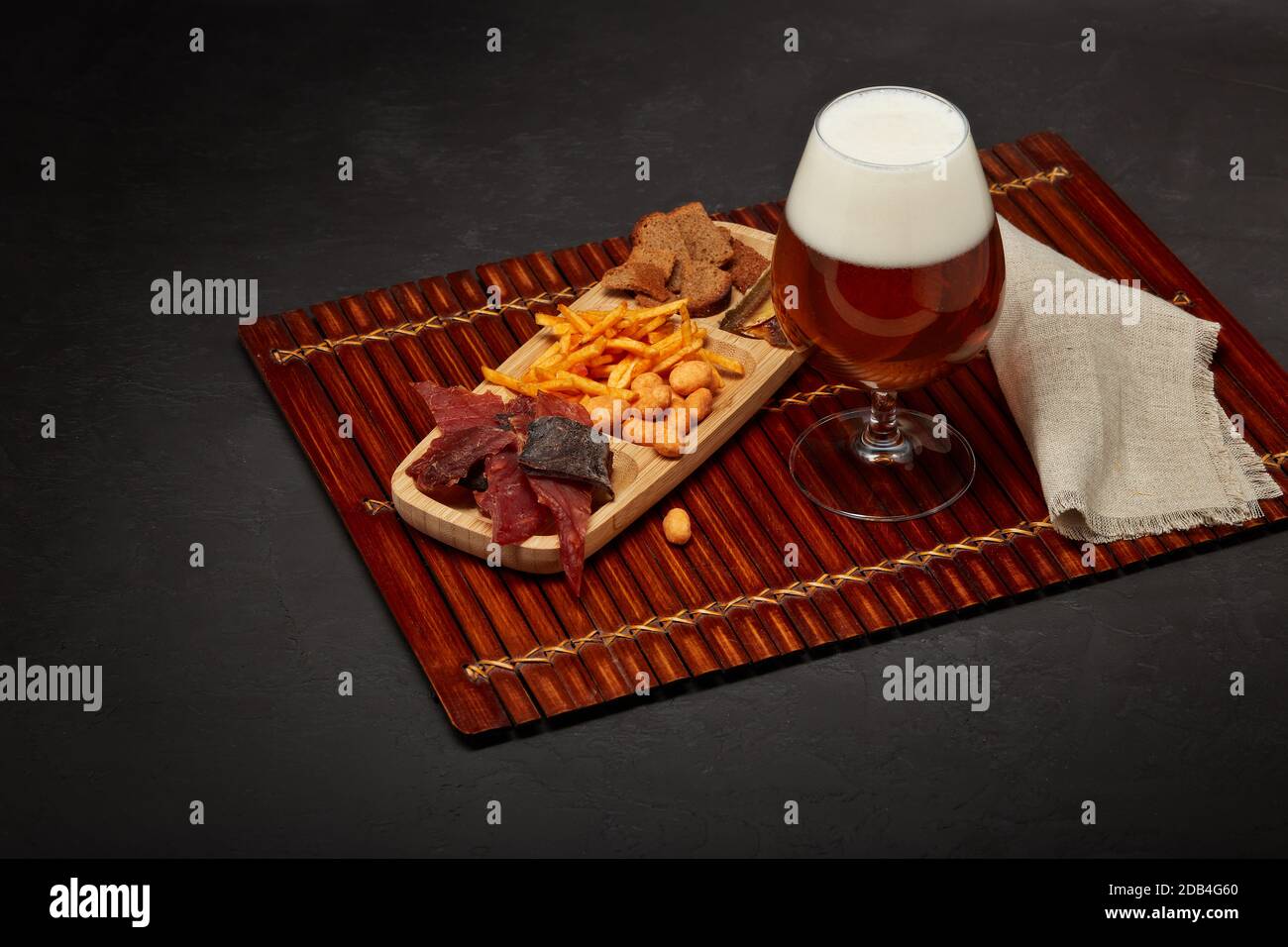 Glass with beer and set of various kind snacks: jerky, potato chips ...