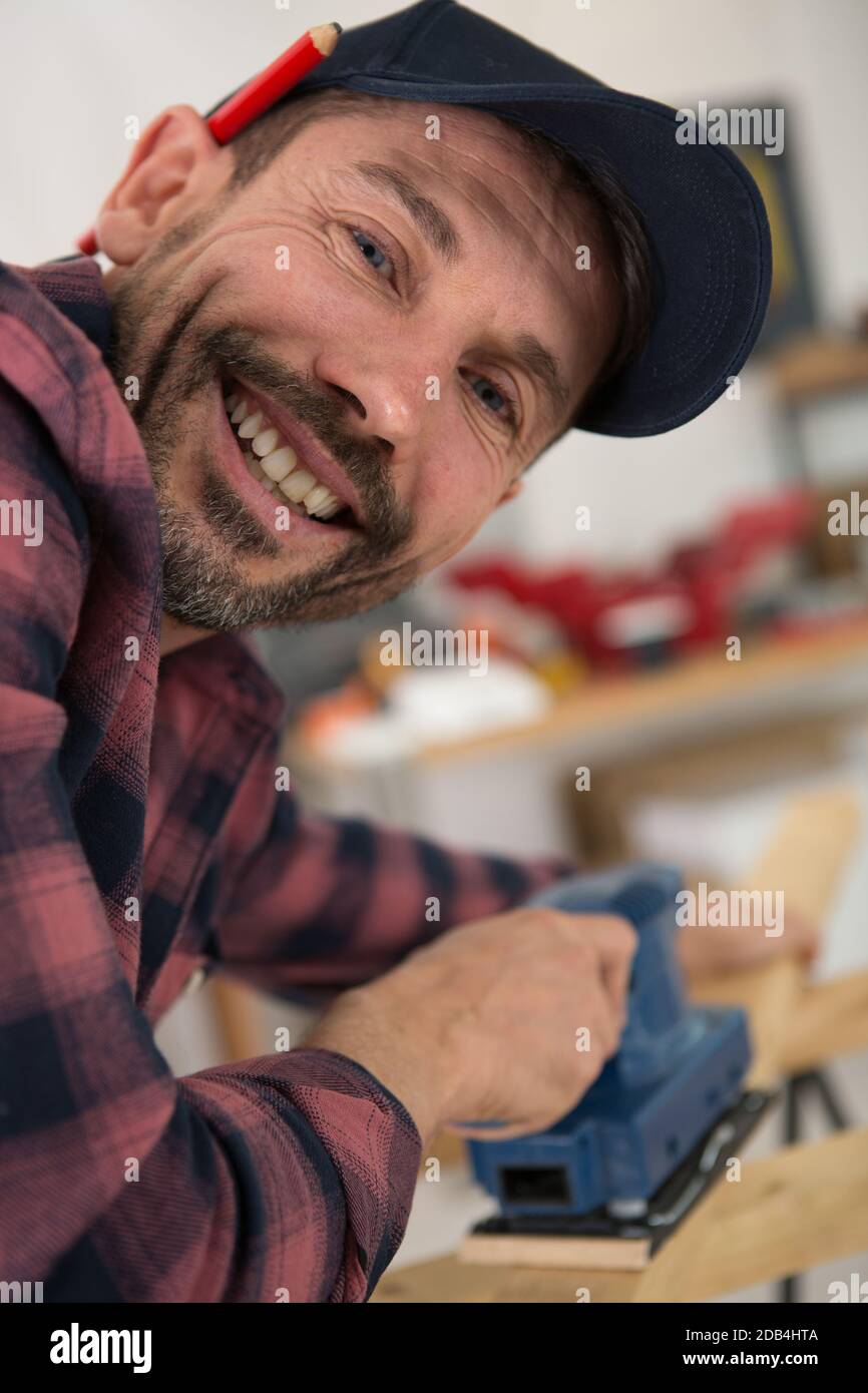 smiling man using an electric sander Stock Photo - Alamy