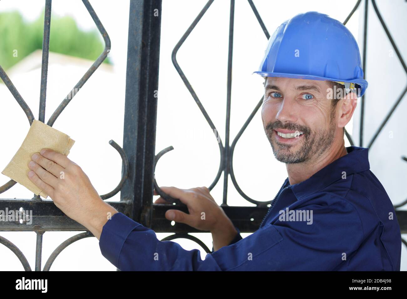 man sanding a metal fence Stock Photo - Alamy
