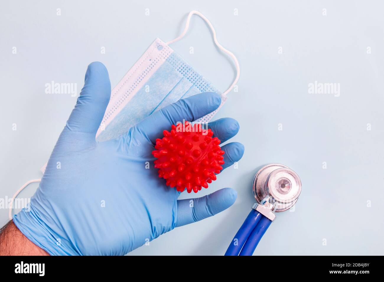 Doctor's hand holding red virus ball concept over a light blue ...