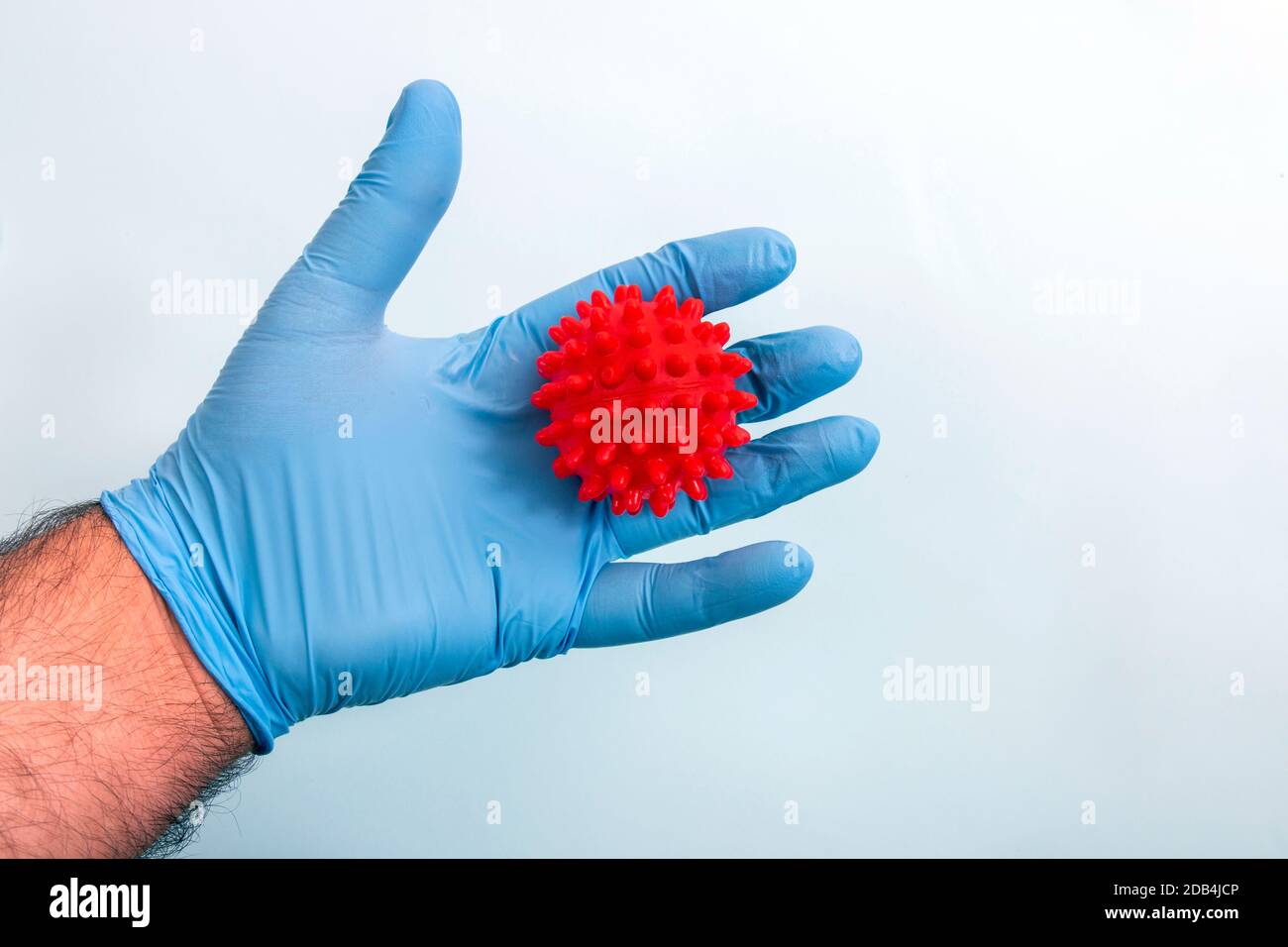 Doctor's hand holding red virus ball concept over a light blue ...