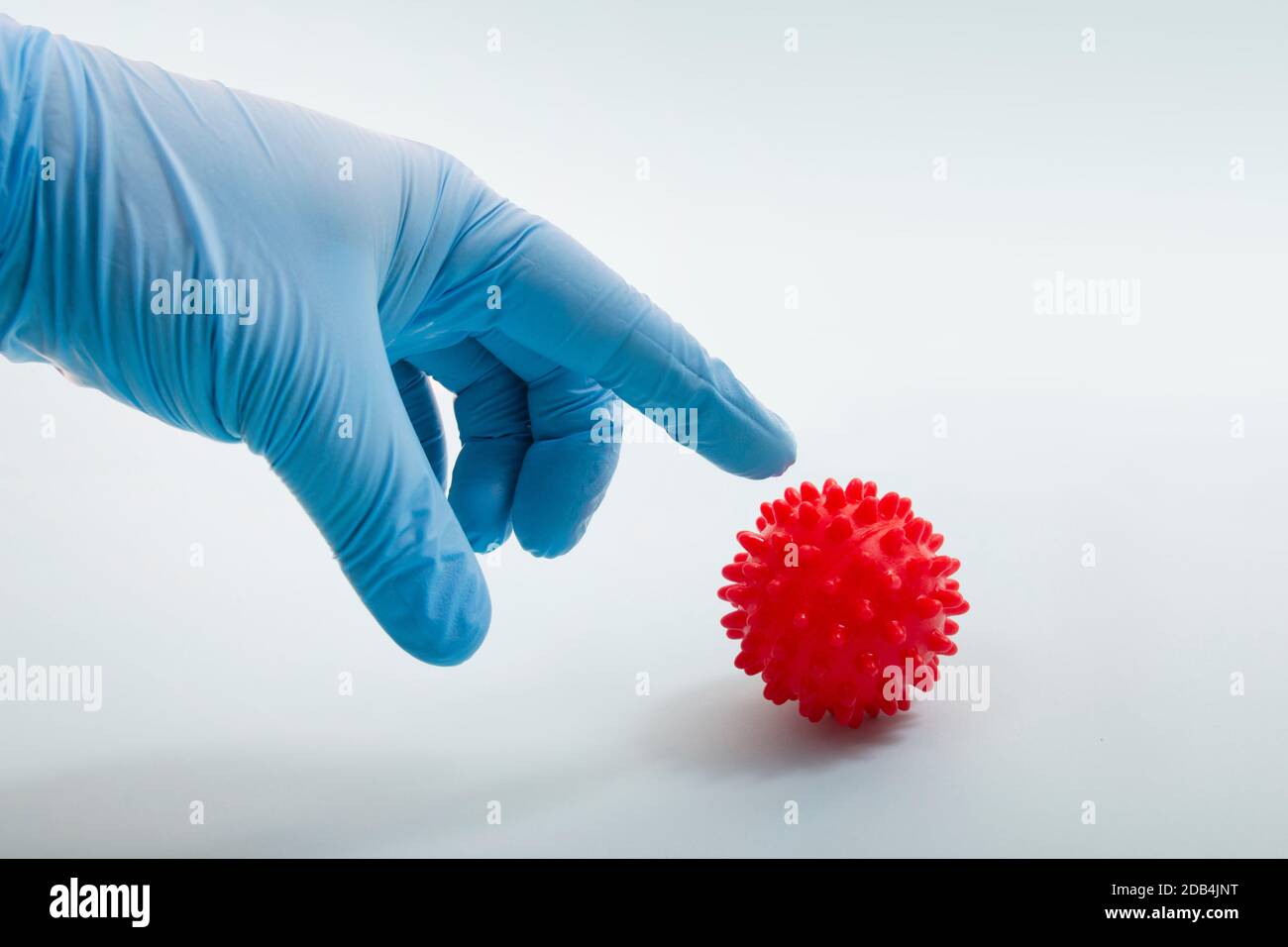 Doctor's hand pointing to red virus ball concept over a light blue ...
