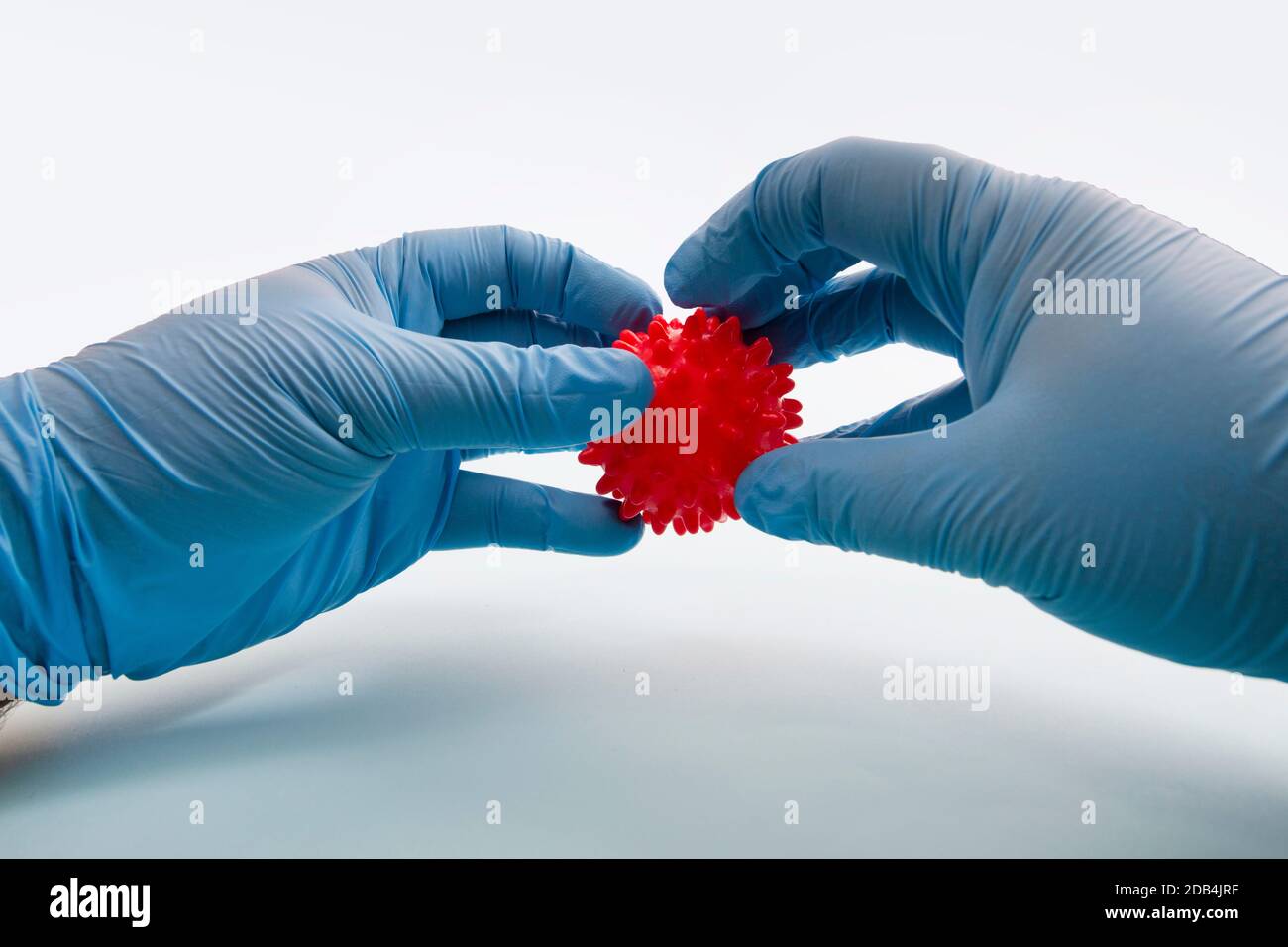 Doctor's hand holding red virus ball concept over a light blue ...