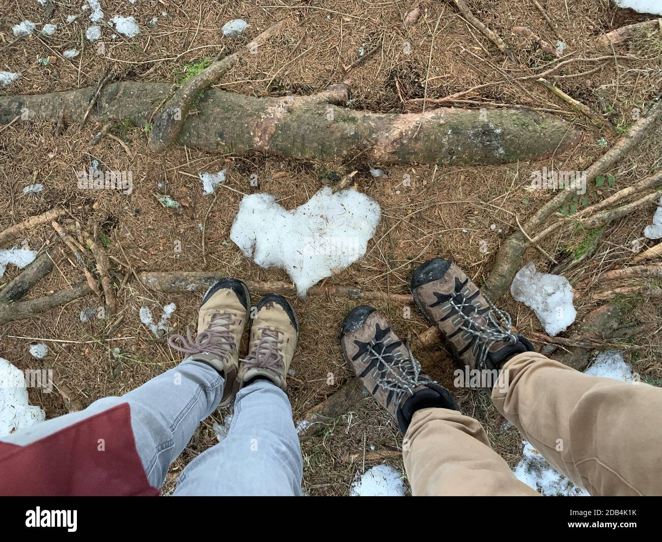 A high angle shot of feet wearing sneakers standing on the snowy ground ...