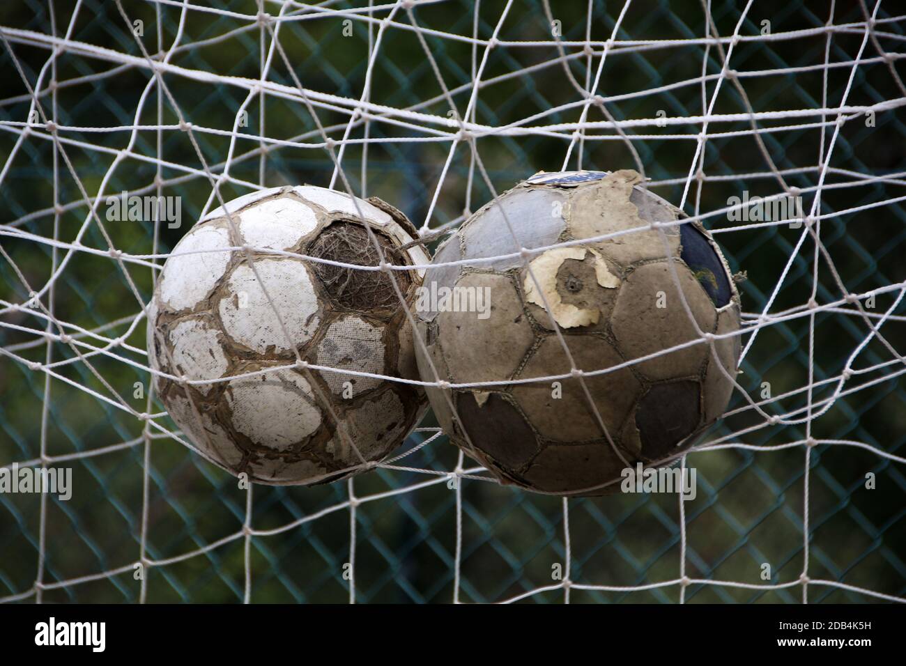 Close view of two old soccer balls in soccer goal net Stock Photo - Alamy