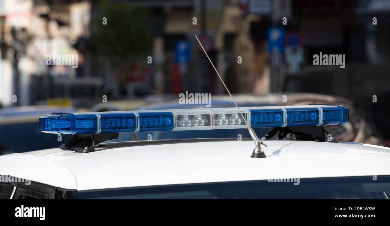 Blue light flasher at police car top closeup view, blur cityscape ...
