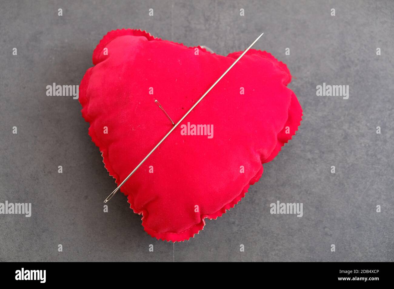 red pincushion and a large sewing needle, needle spell Stock Photo - Alamy