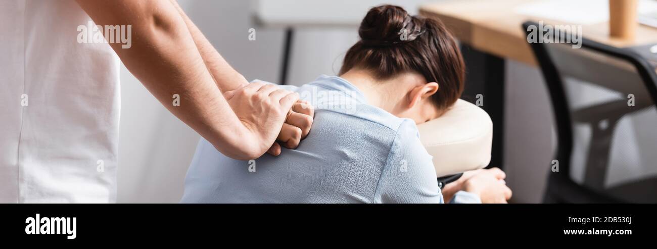 Masseur massaging female client back sitting on massage chair with ...