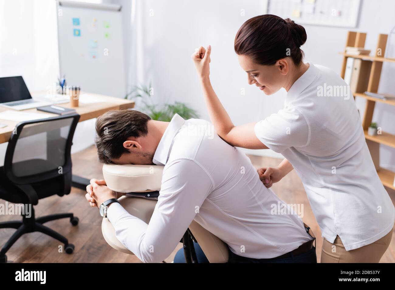 Smiling masseuse doing back massage with elbow for businessman in ...