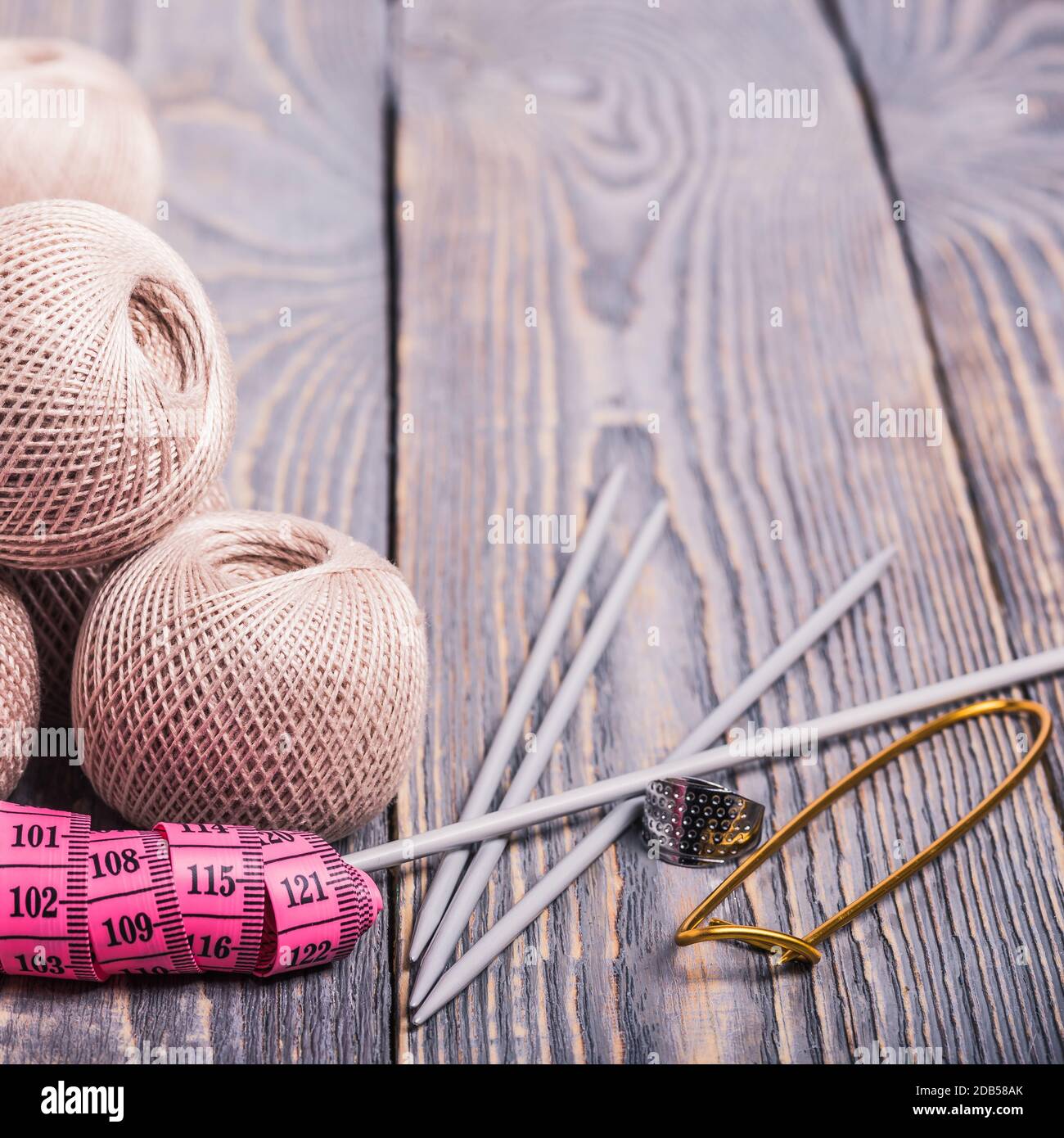 Balls of yarn, knitting needles and measuring tape on a wooden ...