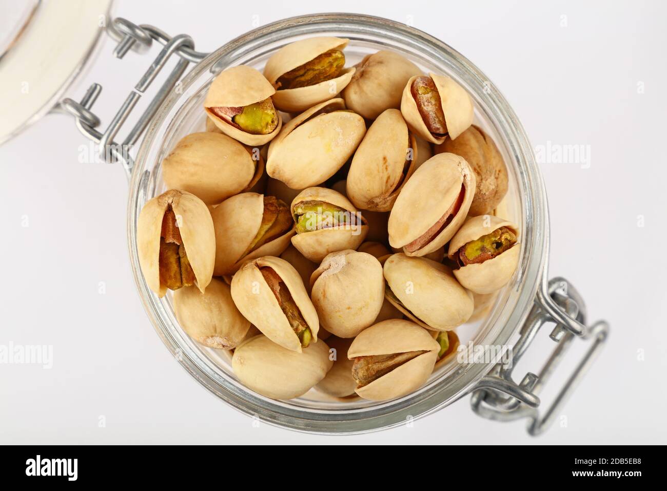 Close up fresh roasted pistachio nuts in glass jar over white ...