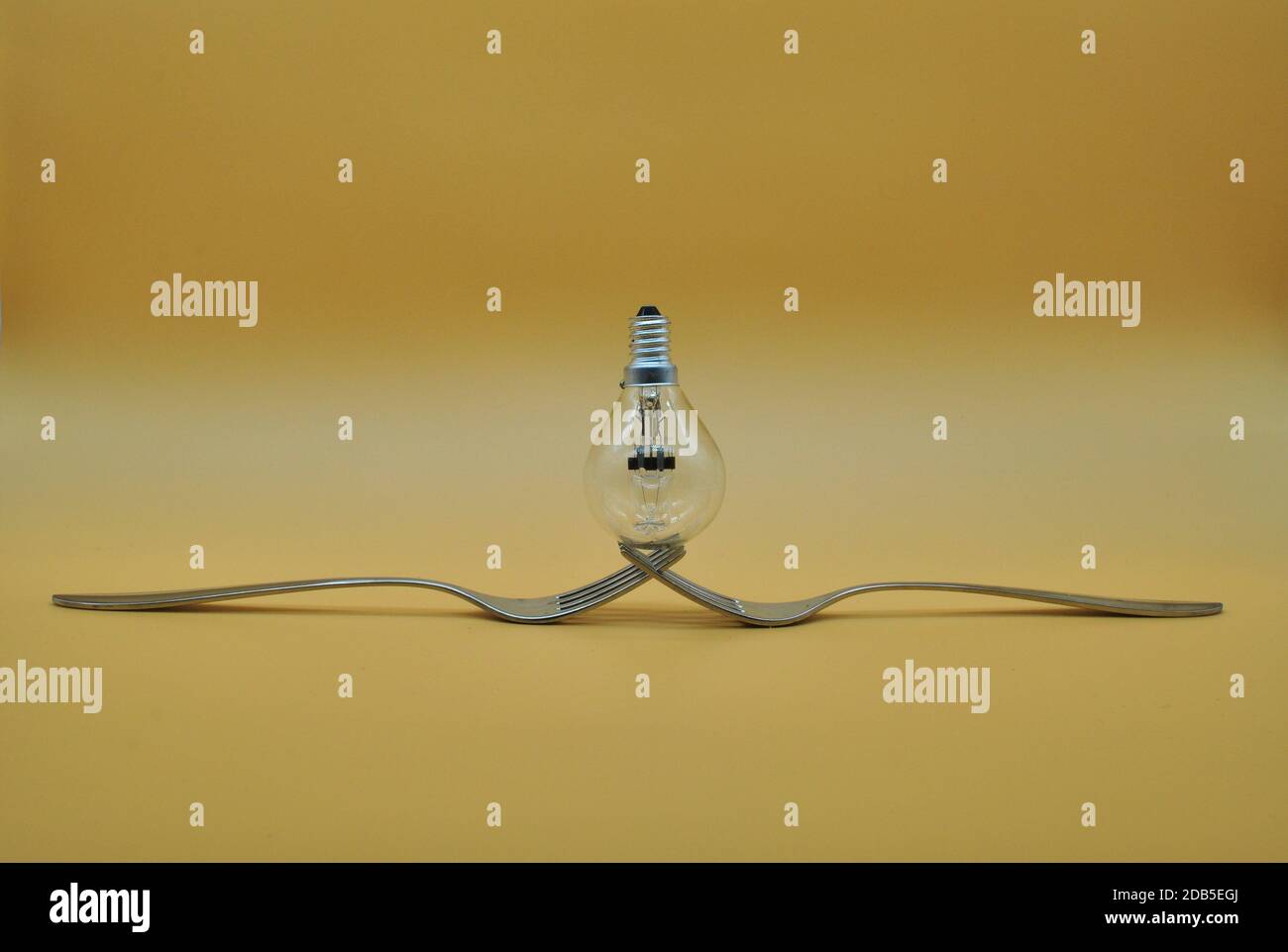 light bulb balancing on composition of 2 intertwined forks isolated on ...
