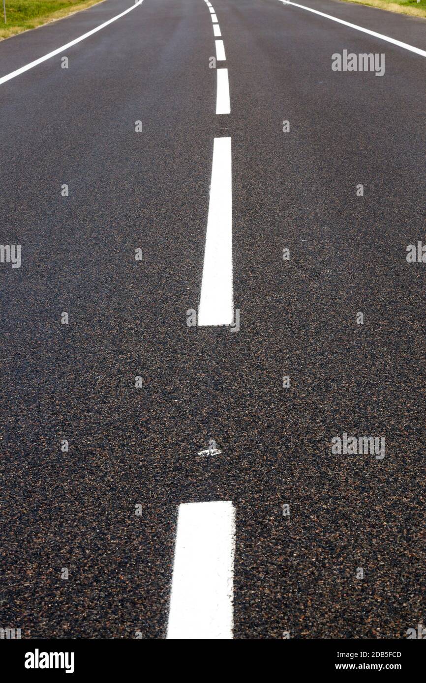 white road markings defining the order of traffic on the asphalt road ...