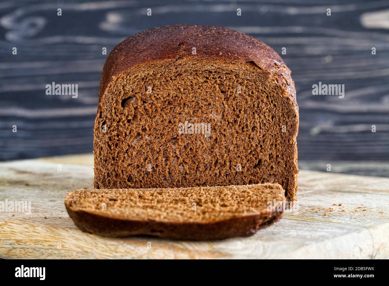 black made from rye flour square loaf of bread sliced on wooden cutting ...