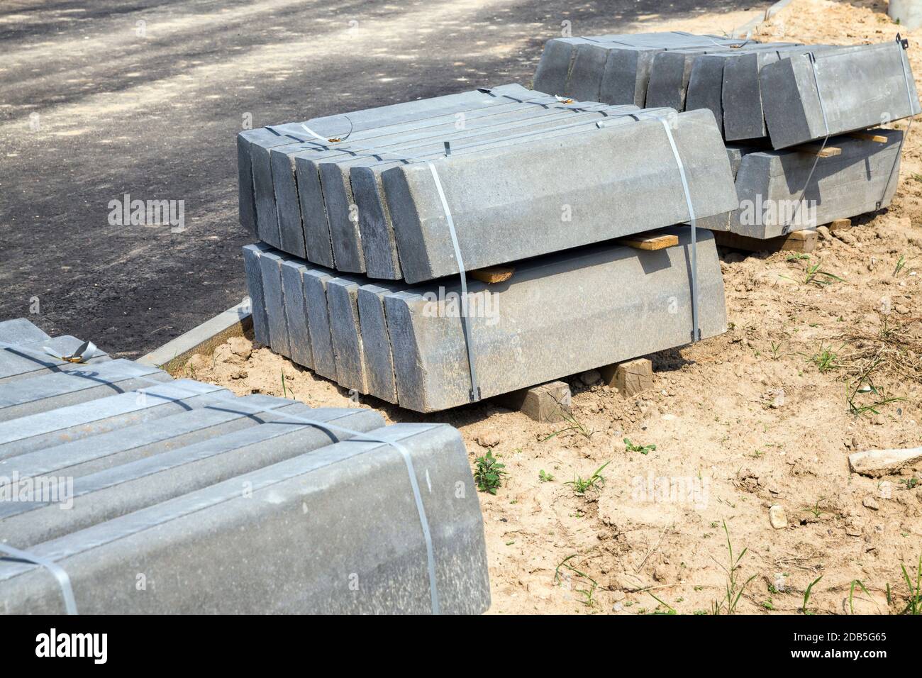 Packed large and long new concrete blocks for curbs, lying on the ...
