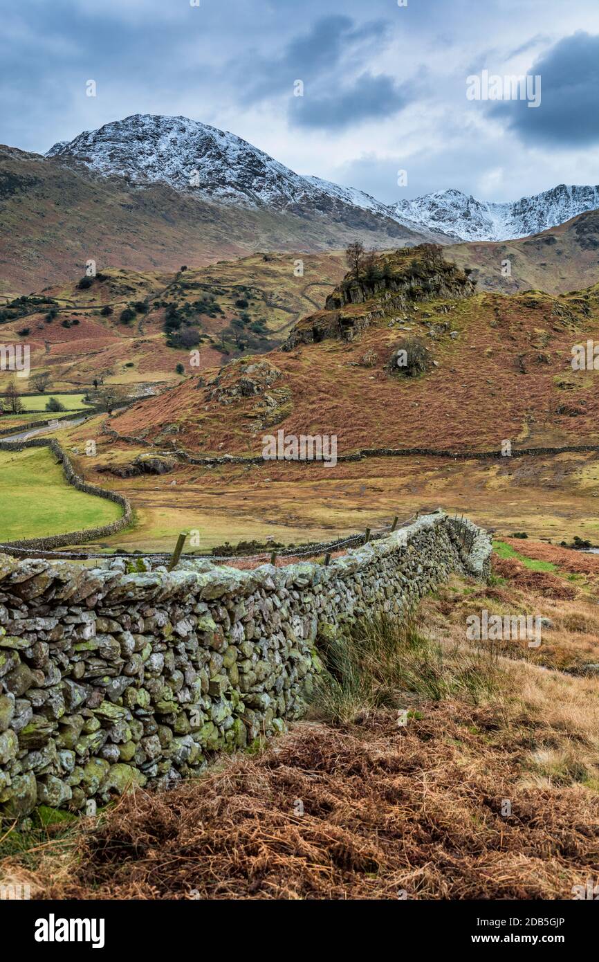 Long rural stone wall leading though Cumbrian valley with crags and ...