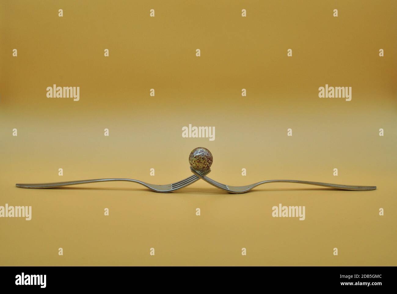 marble in perfect balance on a composition of 2 intertwined forks ...