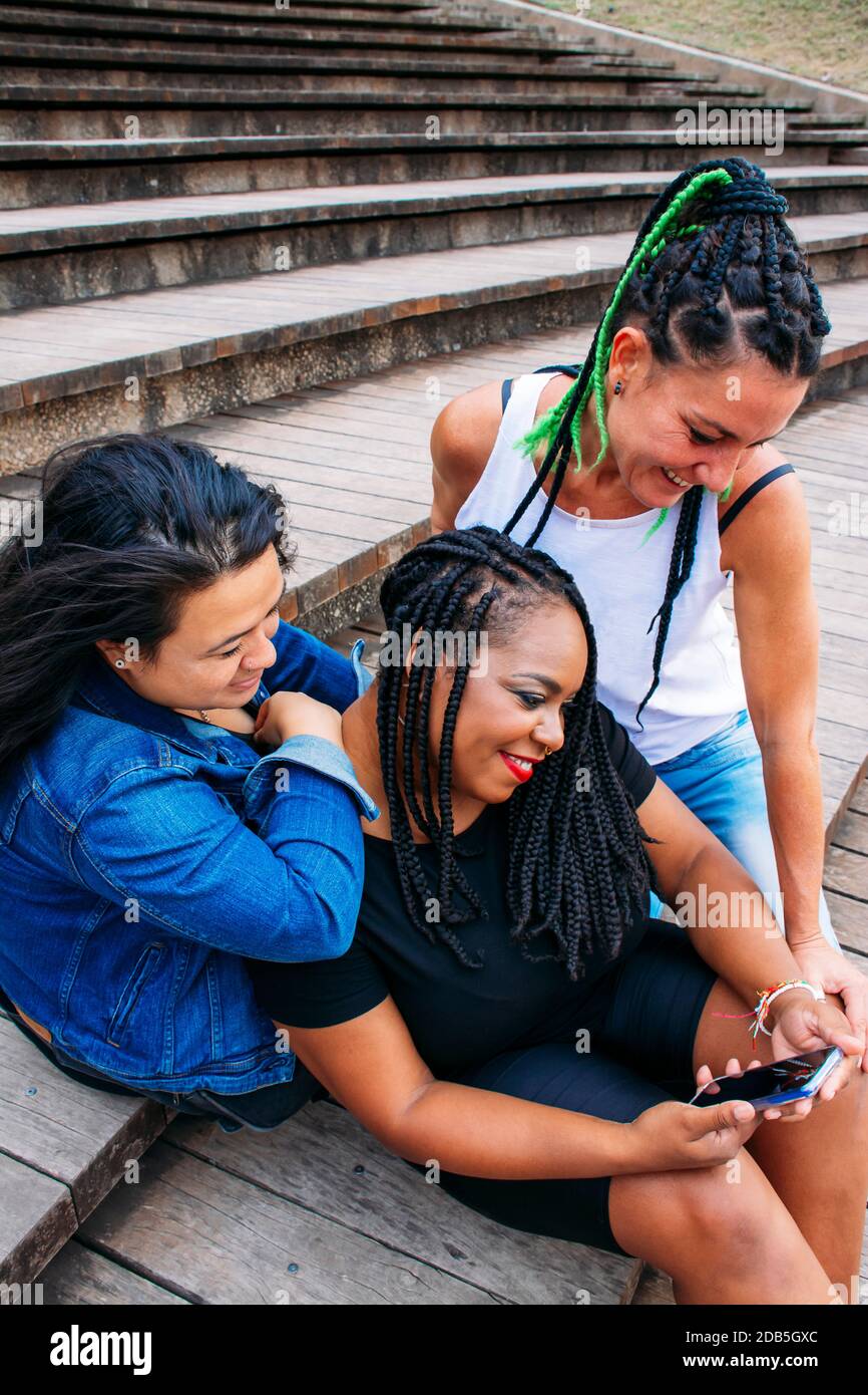 Group of smiling young women of diverse races sharing fun moments using ...