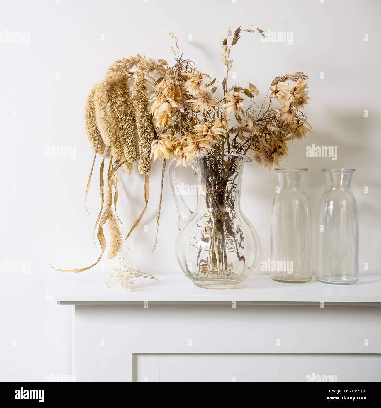 Dried flowers and cereals in a transparent glass decanter stand on a ...