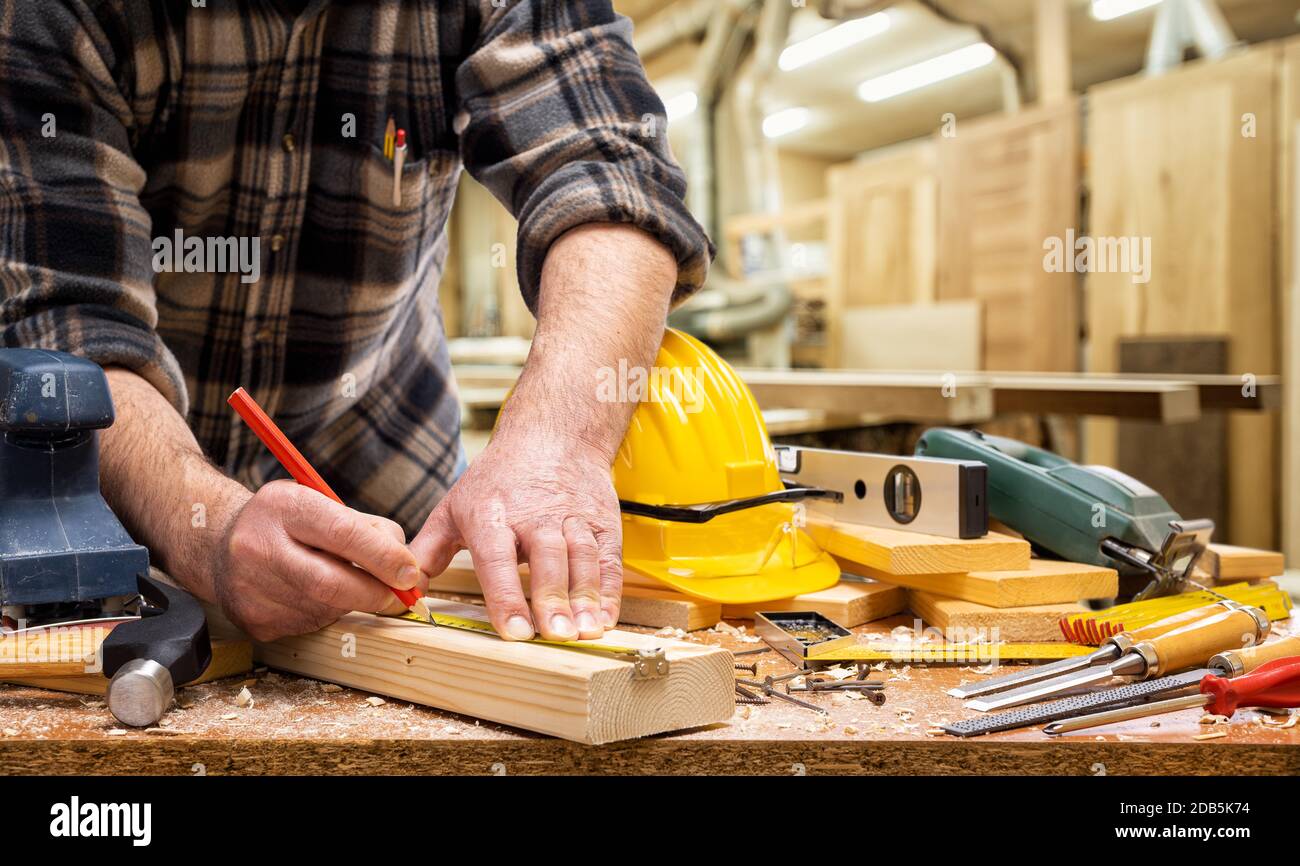 Close-up. Carpenter with pencil and the meter marks the measurement on ...