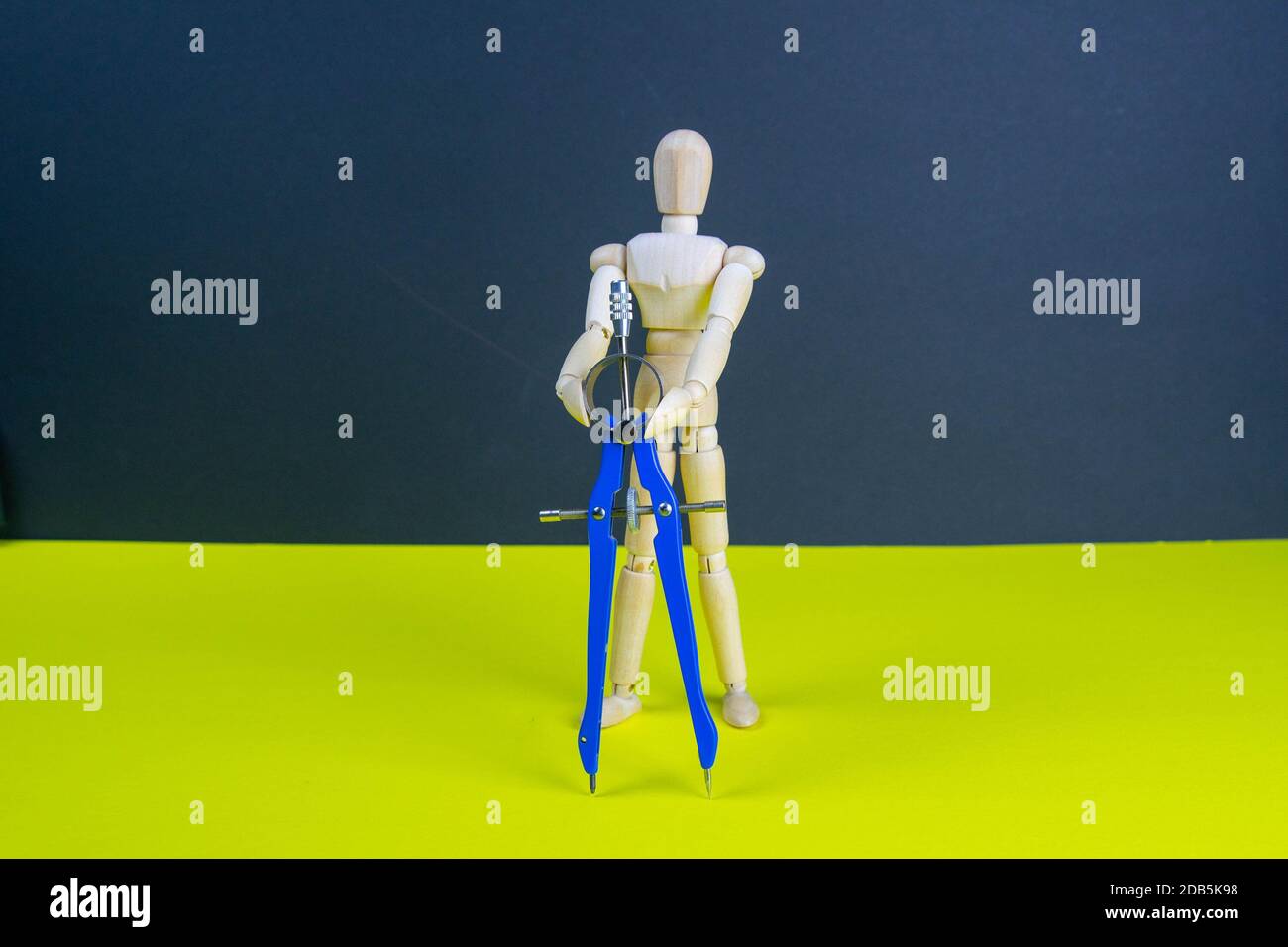 Wooden man figurine with compass on the yellow table Stock Photo - Alamy