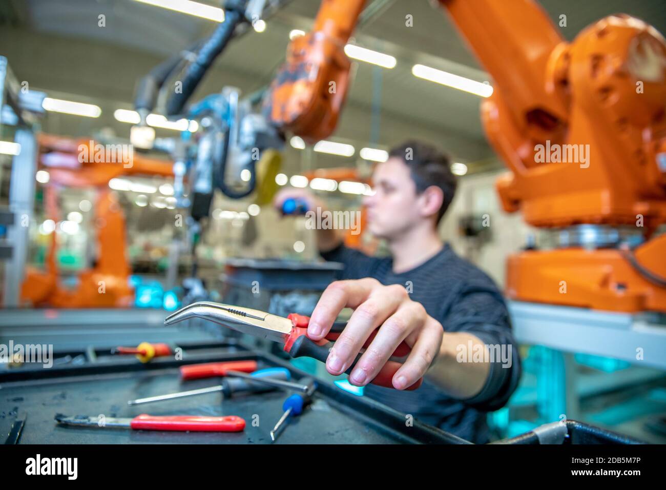 Technical worker performs maintenance robotic arms on the production ...
