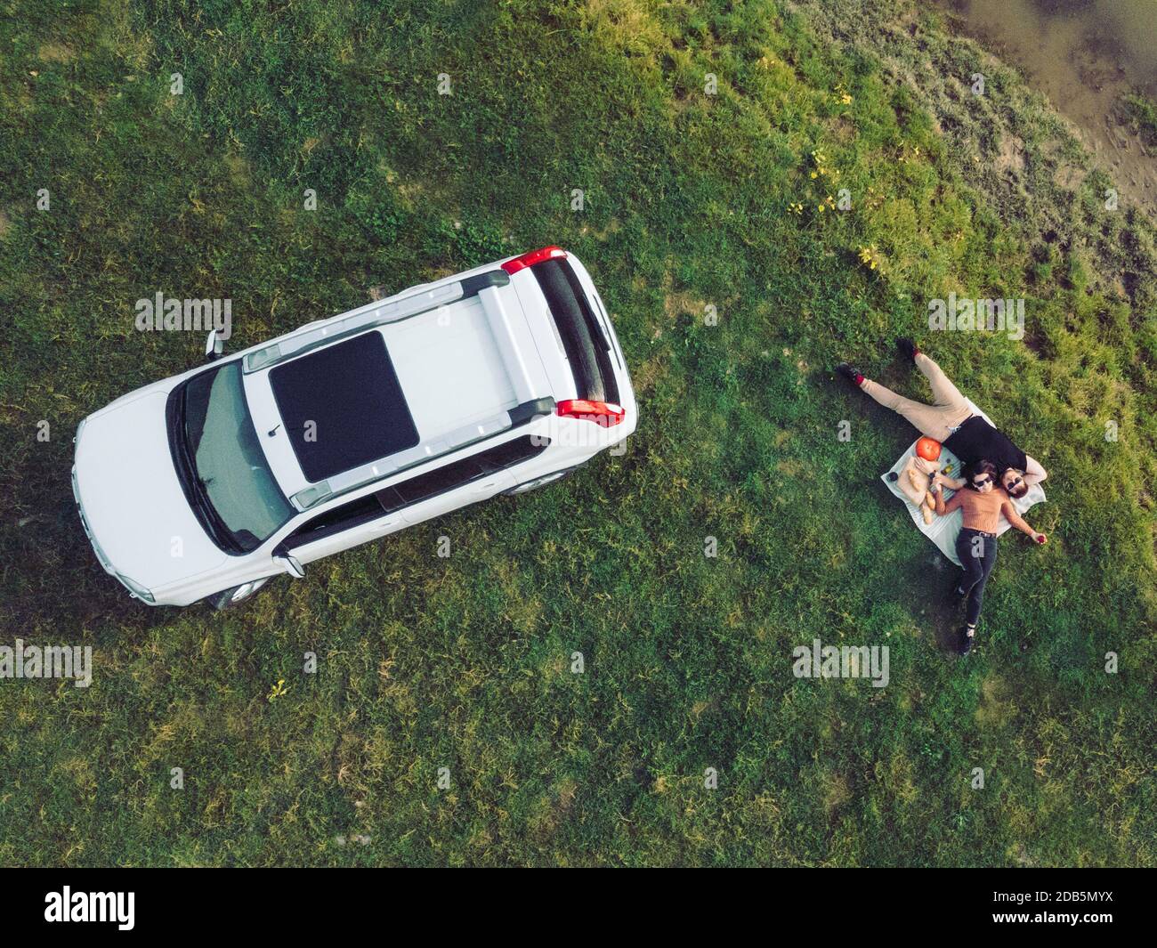 overhead top view of suv car and couple laying down on a blanket at ...